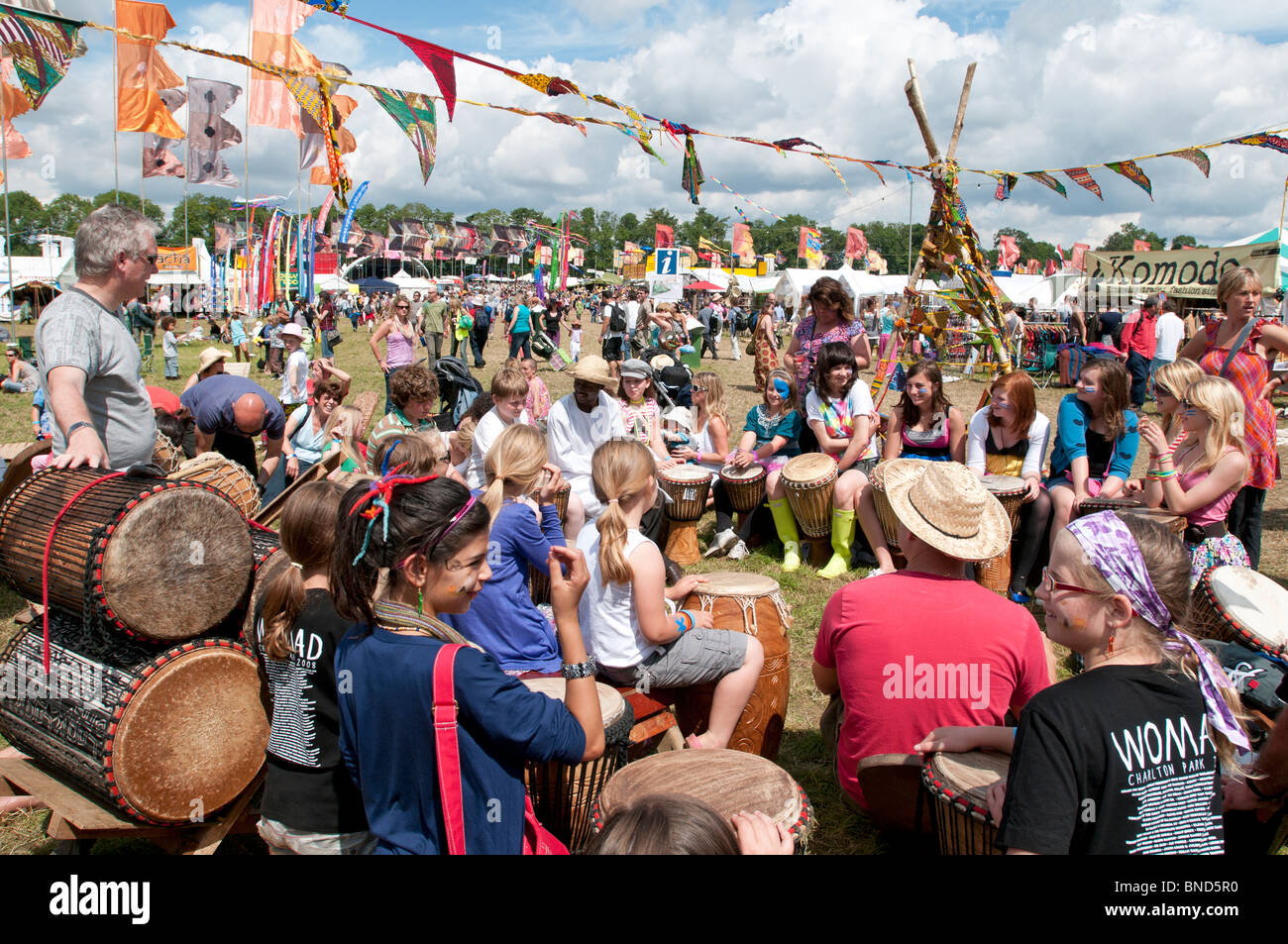 A big crowd of families sitting in a circle enjoying a drumming class ...
