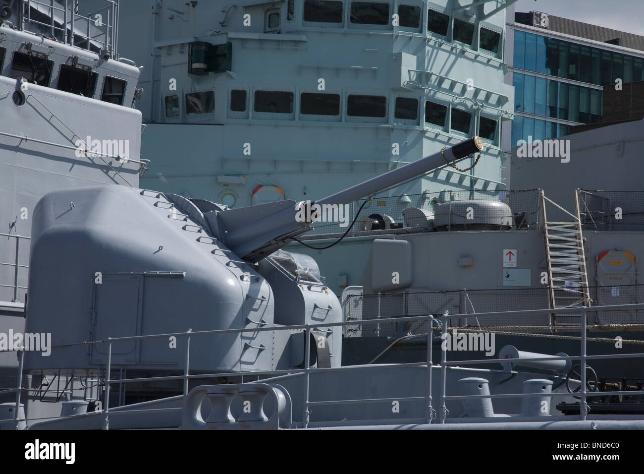 Modern 100 mm Gun on a French Navy Frigate moored next to the British World war two battleship ...