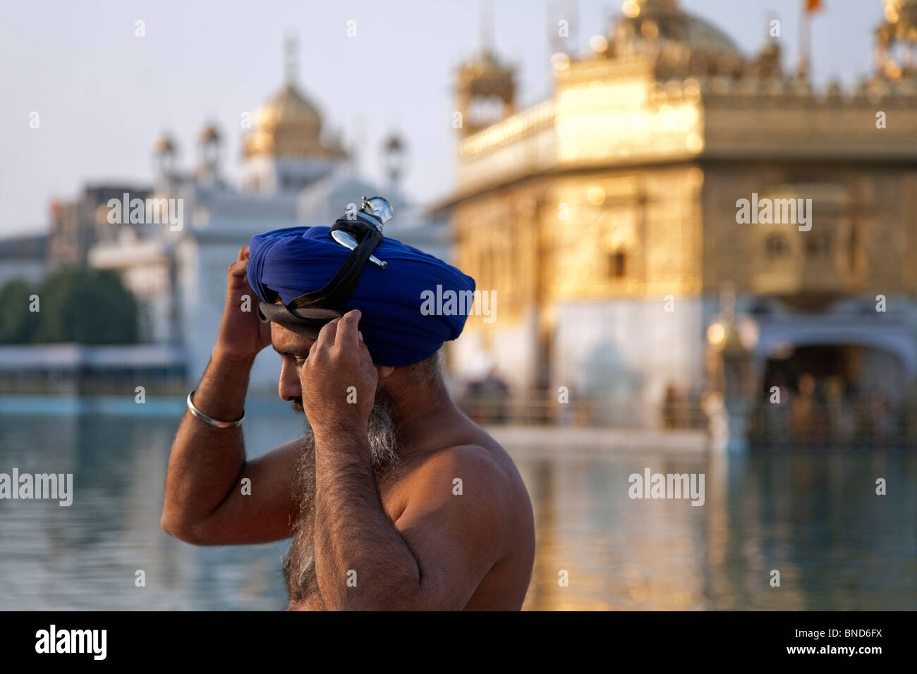 Sikh man adjusting his turban (pagri) and the traditional knife (kirpan ...