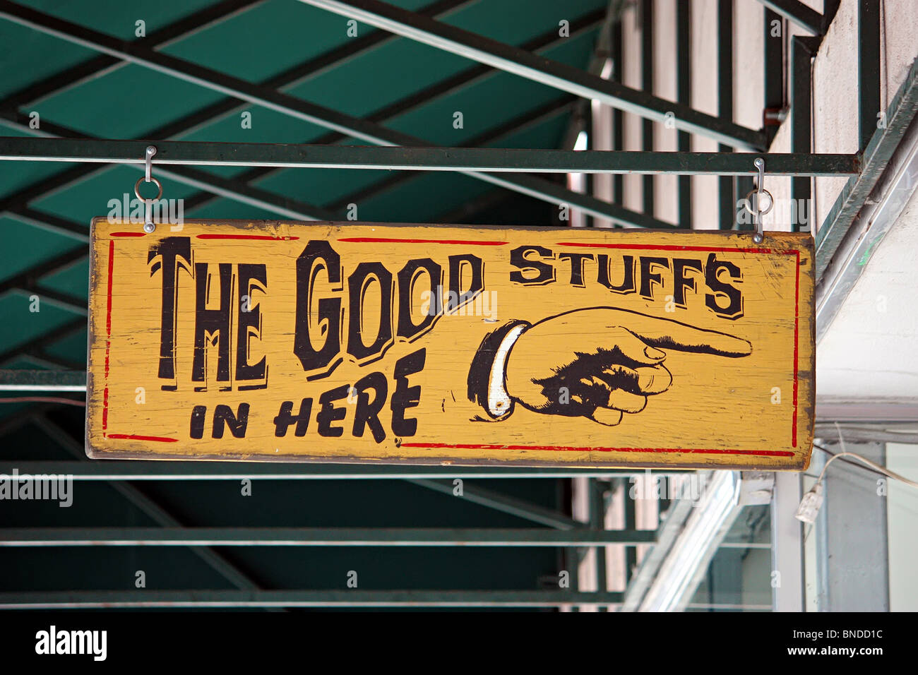 Rectangular wooden yellow sign suspended from metal framework. Words ...