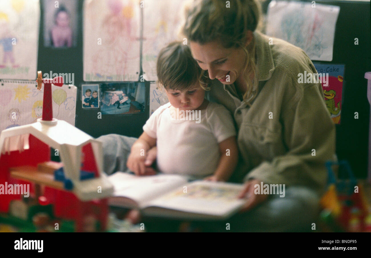 Mother with baby sitting and reading book Stock Photo - Alamy