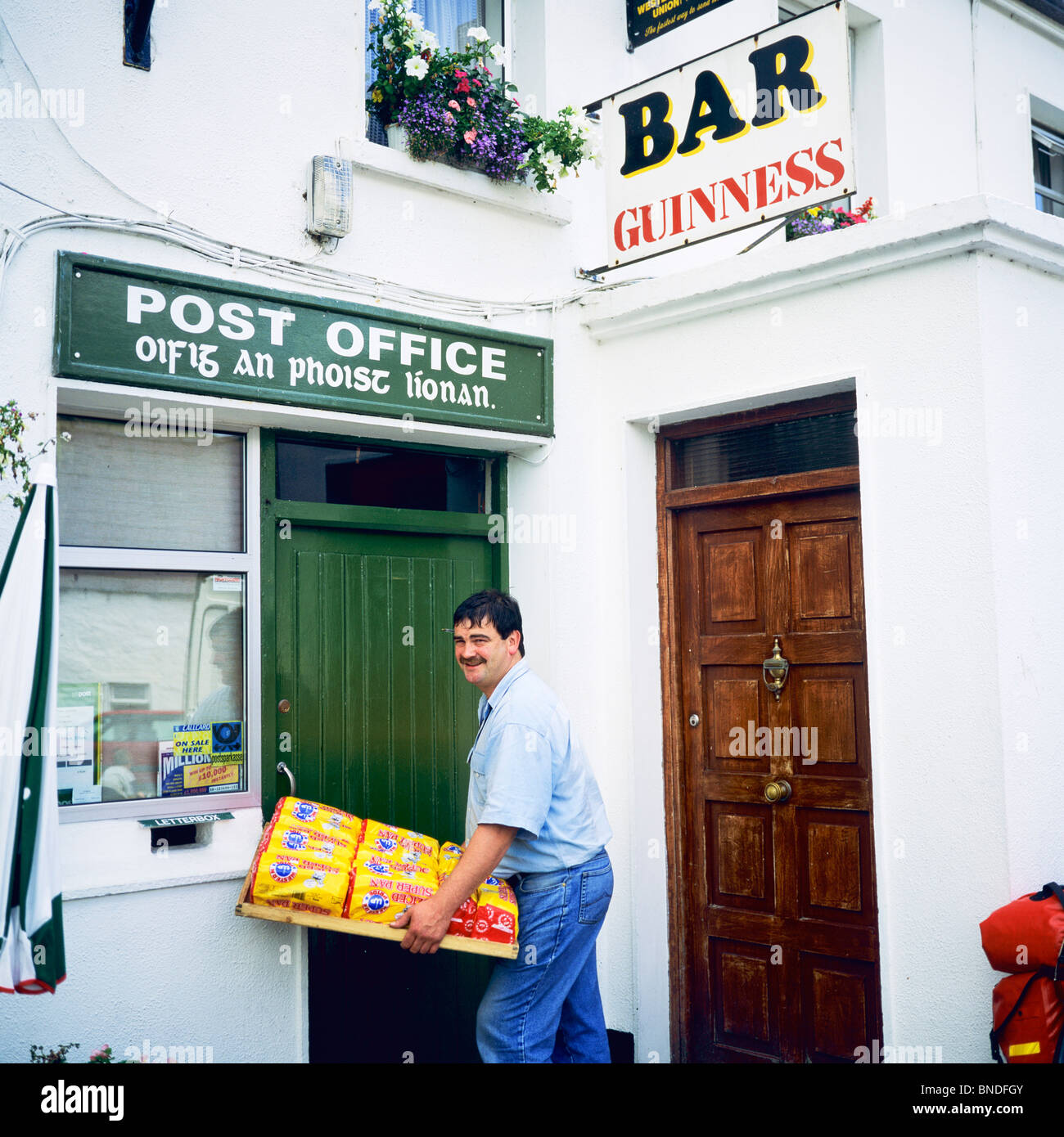 Smiling man delivering grocery to Post Office, bar Guinness sign ...