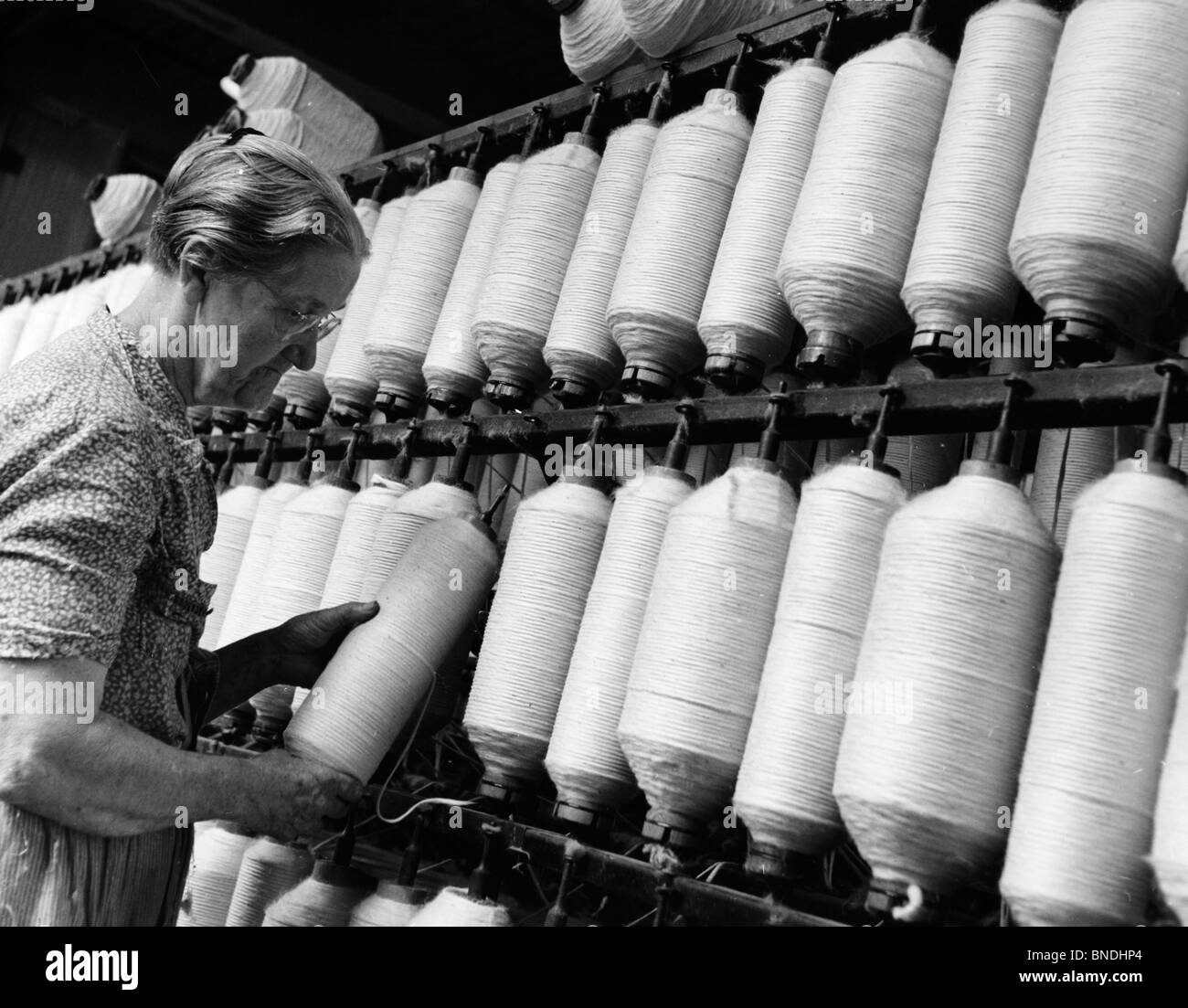 Side profile of a senior woman holding a spool in a textile factory ...
