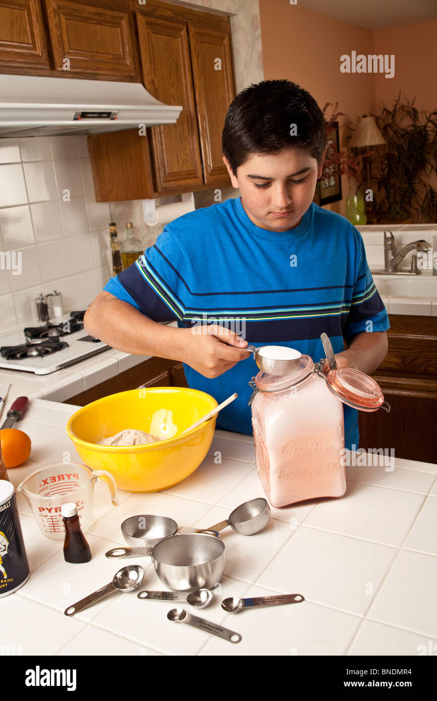 13-14 year old Hispanic boy measuring cooking ingredients. MR © Myrleen ...