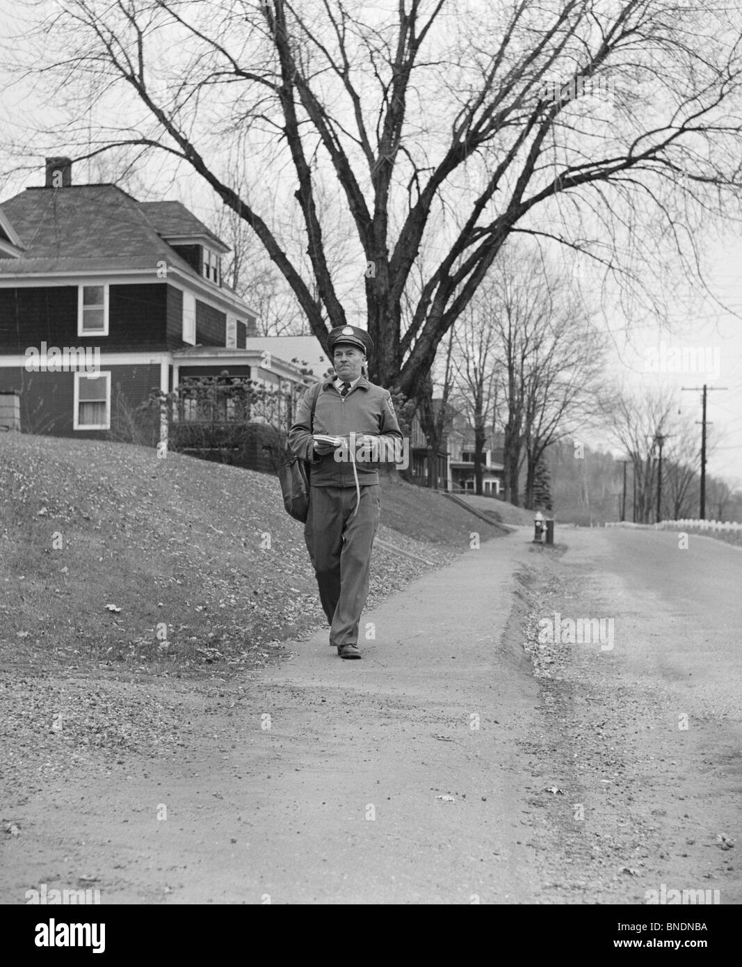 Postman walking with his mail bag Stock Photo - Alamy