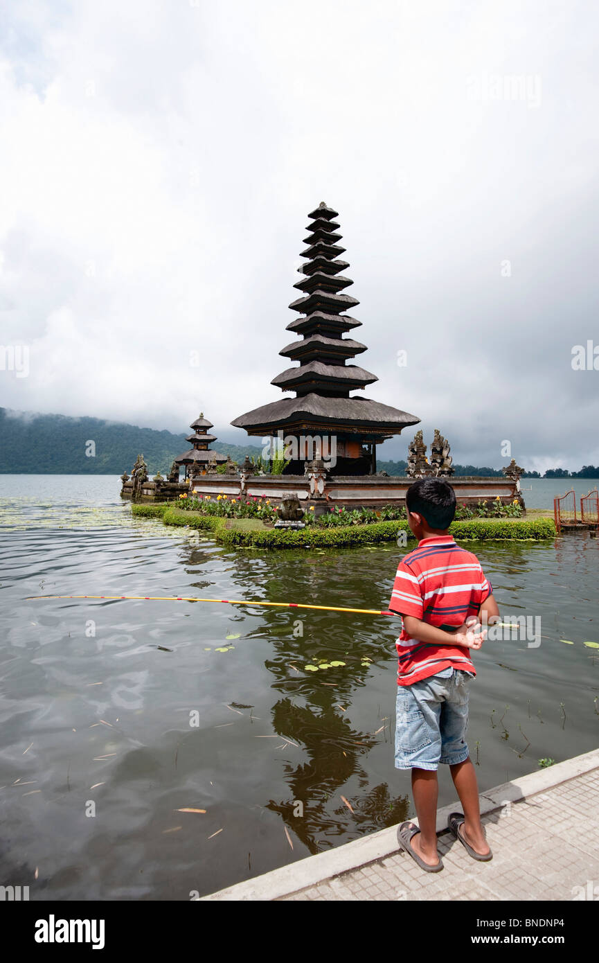A young boy fishing at the Ulan Danu Beratan temple on Lake Beratan ...