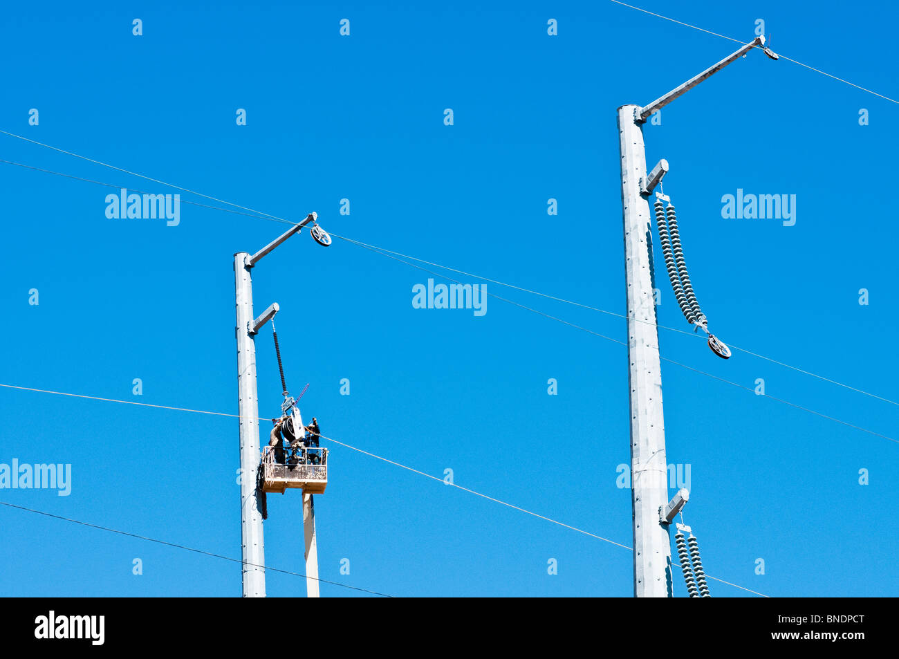 Two construction workers in a cherry picker basket work on a new power ...