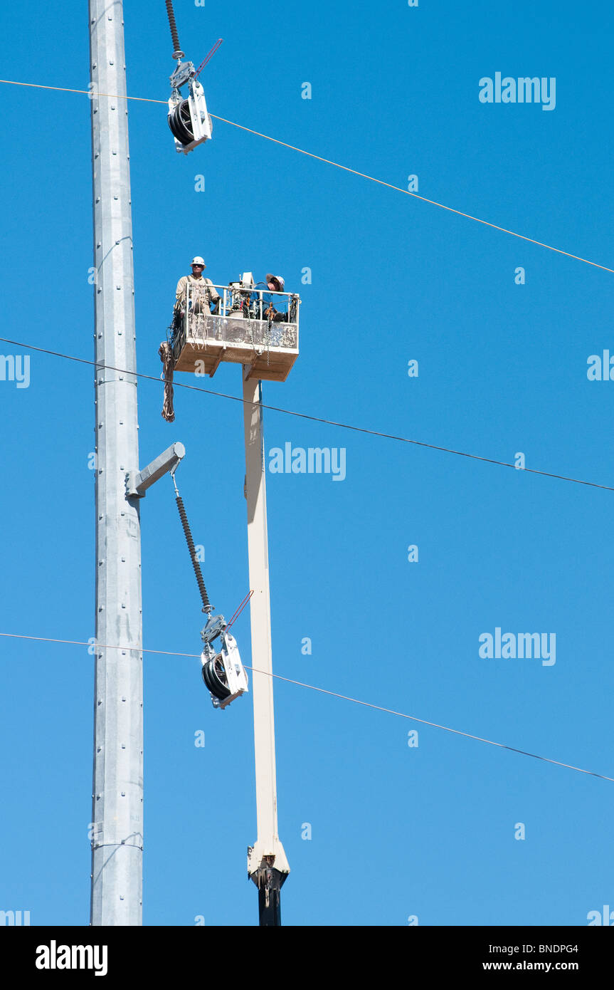 Two construction workers in a cherry picker basket work on a new power ...