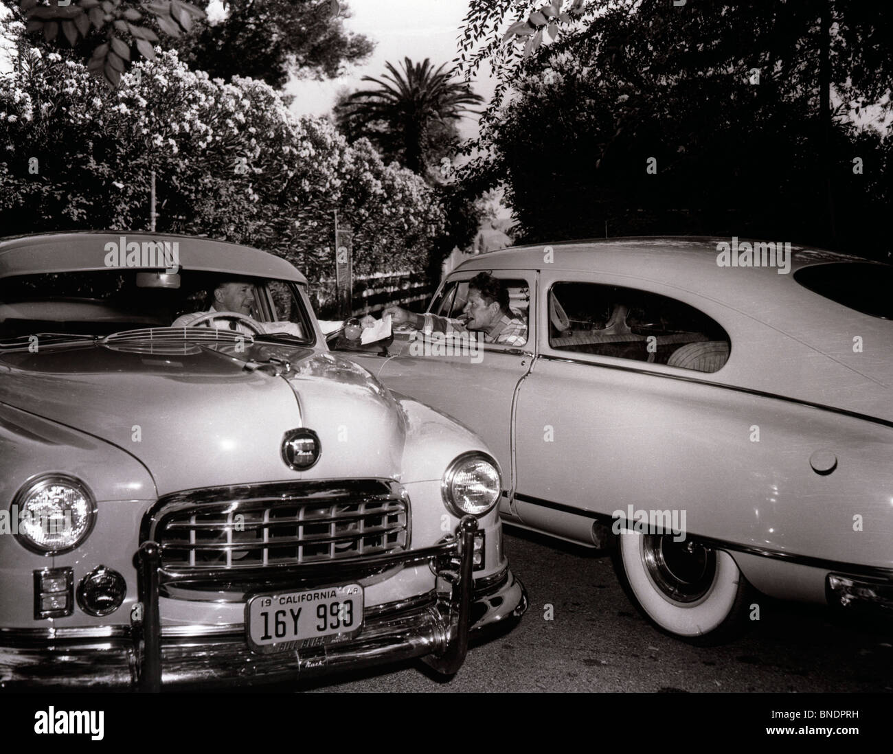 Two men sharing information between cars, 1949 Stock Photo - Alamy