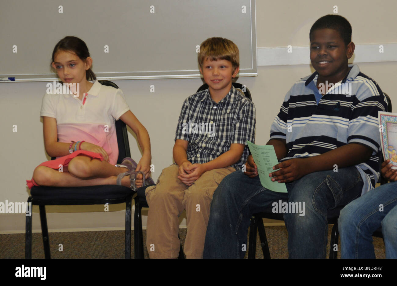 3 small children sitting in a classroom Stock Photo - Alamy