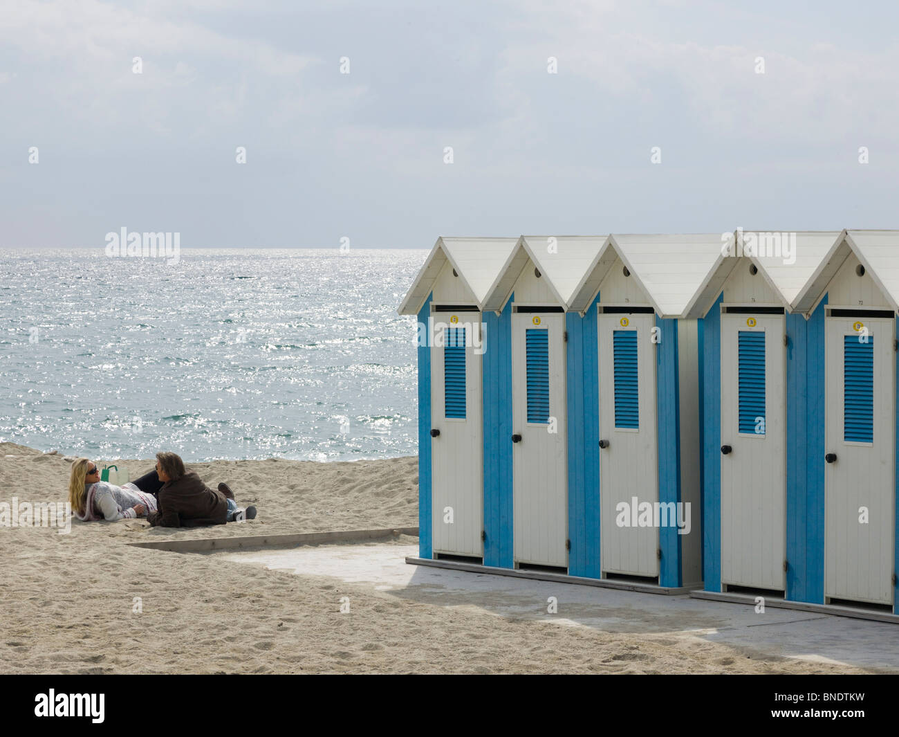 Couple lying on the beach near changing cubicles Stock Photo - Alamy