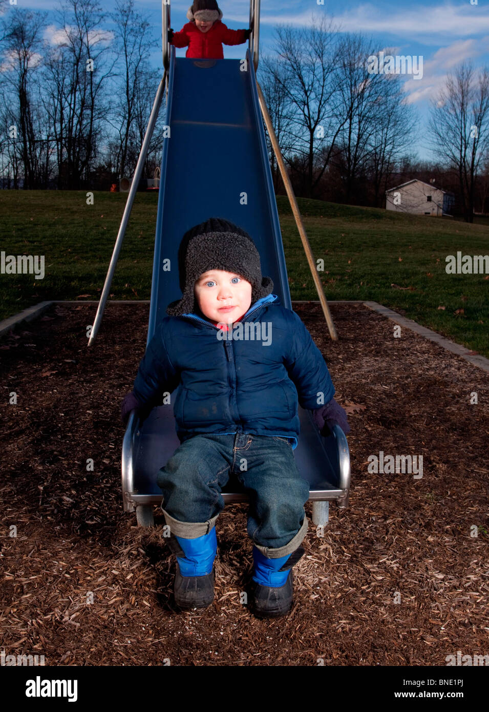 Boys playing on a slide in a park Stock Photo - Alamy