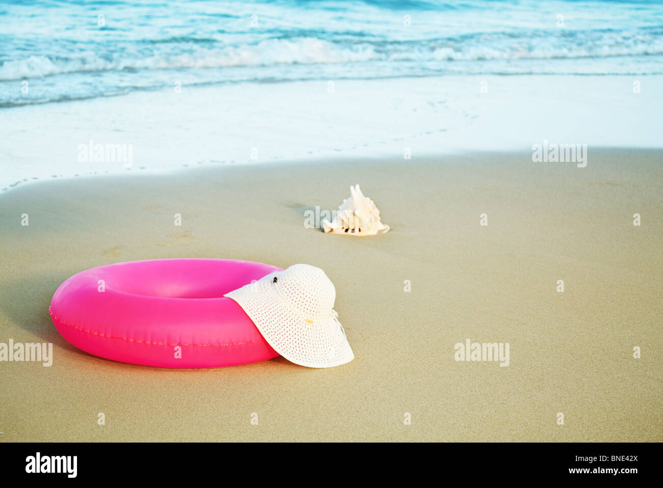 Seashell, inflatable tube and hat on sand Stock Photo - Alamy