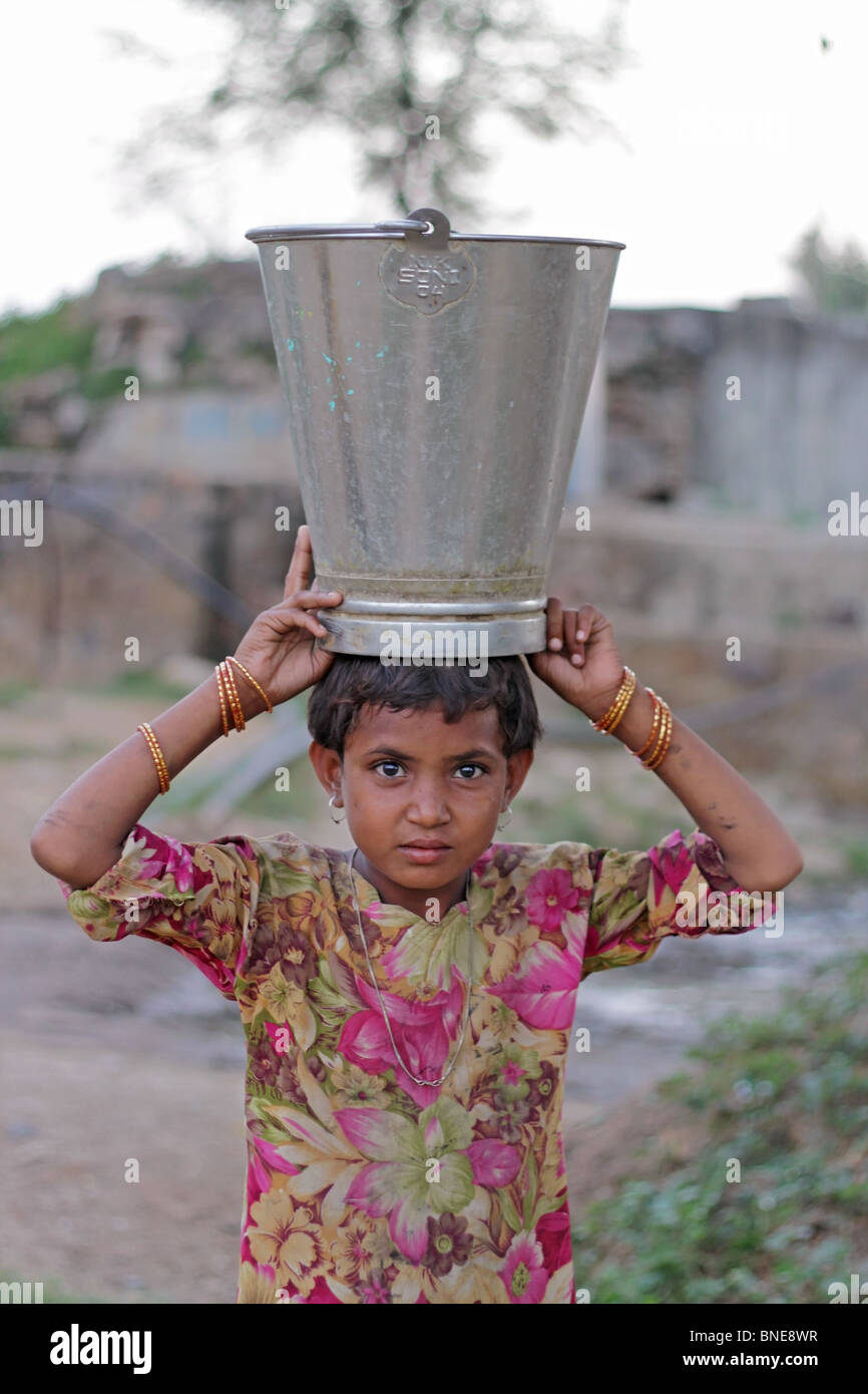 A young girl carrying a bucket on head in a remote village in Rajasthan ...