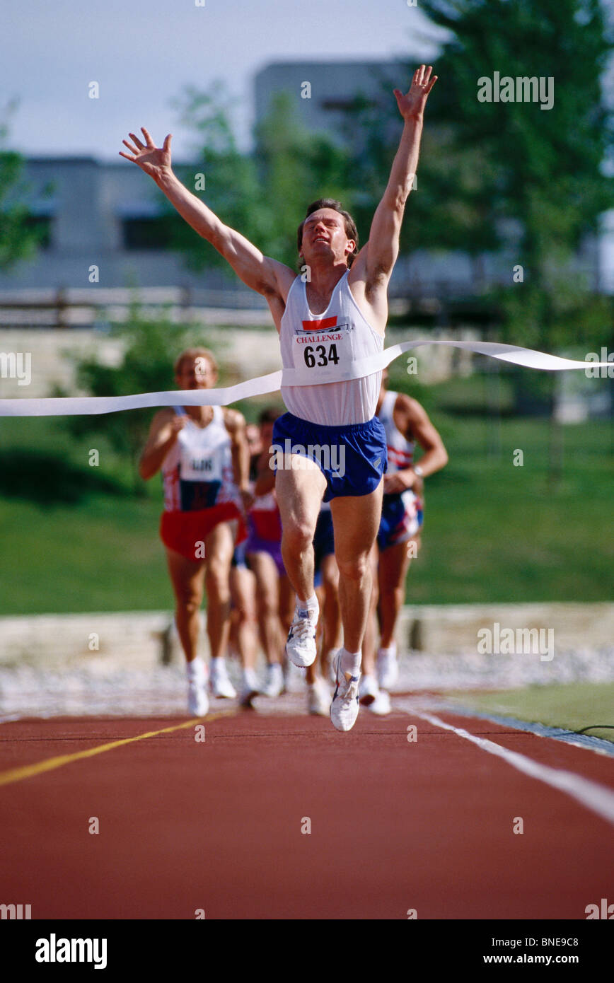 Male runner victorious at the finish line in a track race Stock Photo ...