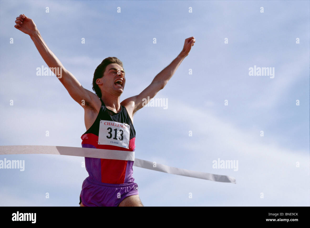 Male runner victorious at the finish line in a track race Stock Photo ...