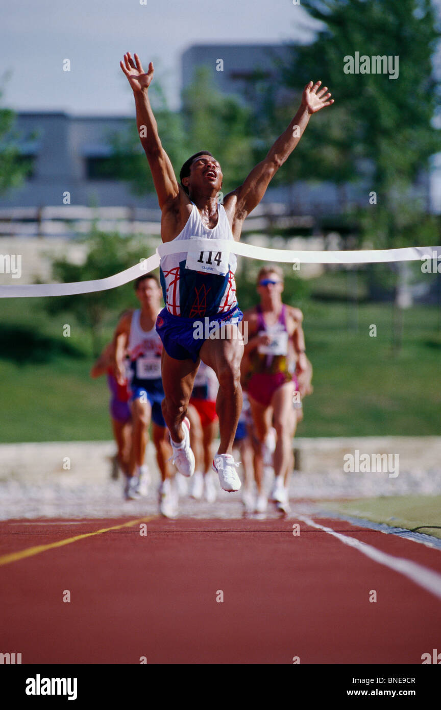 Male runner victorious at the finish line in a track race Stock Photo ...