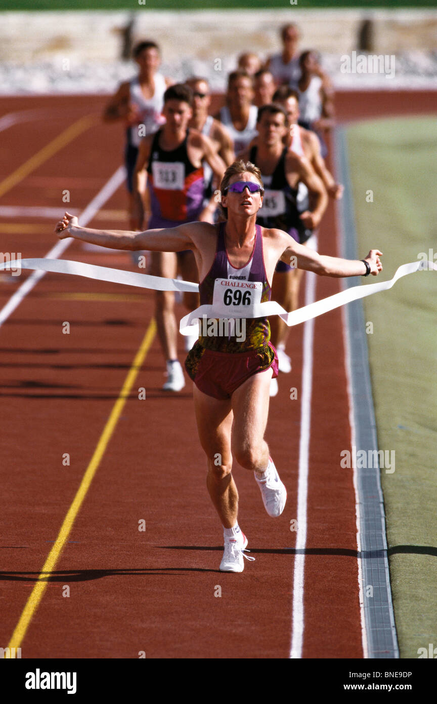 Male runner victorious at the finish line in a track race Stock Photo ...