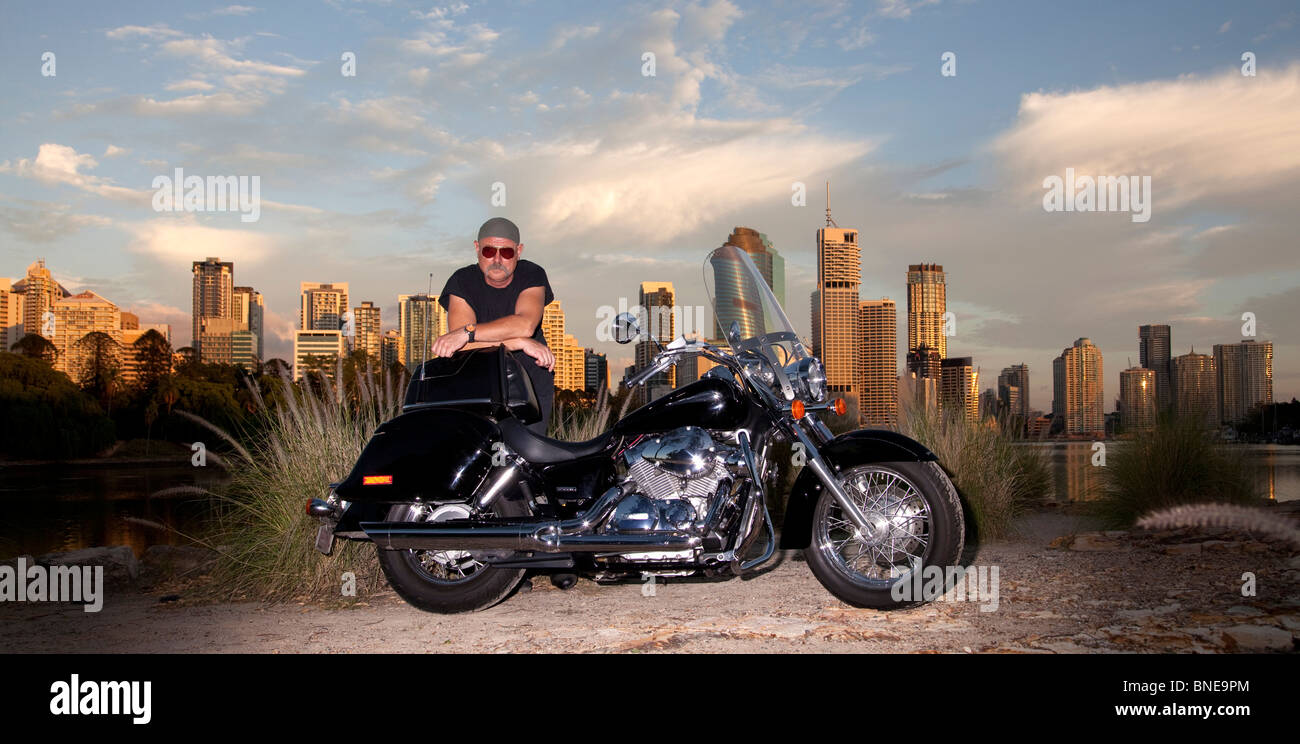 Man on a motorcycle with buildings in the background Stock Photo - Alamy