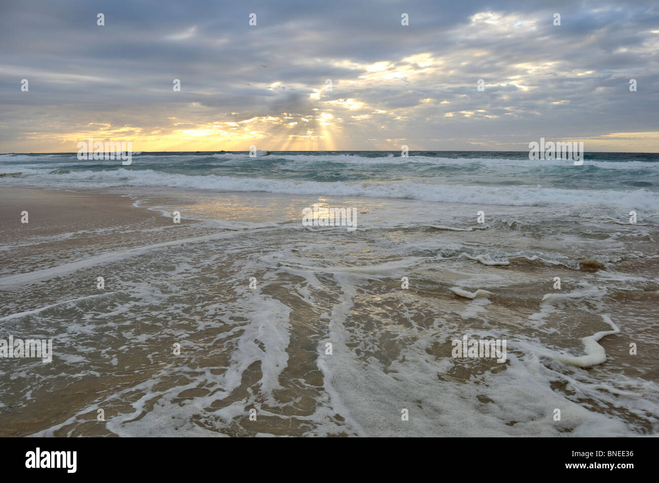 A sunrise high tide brings waves and wash onto the beach Stock Photo ...