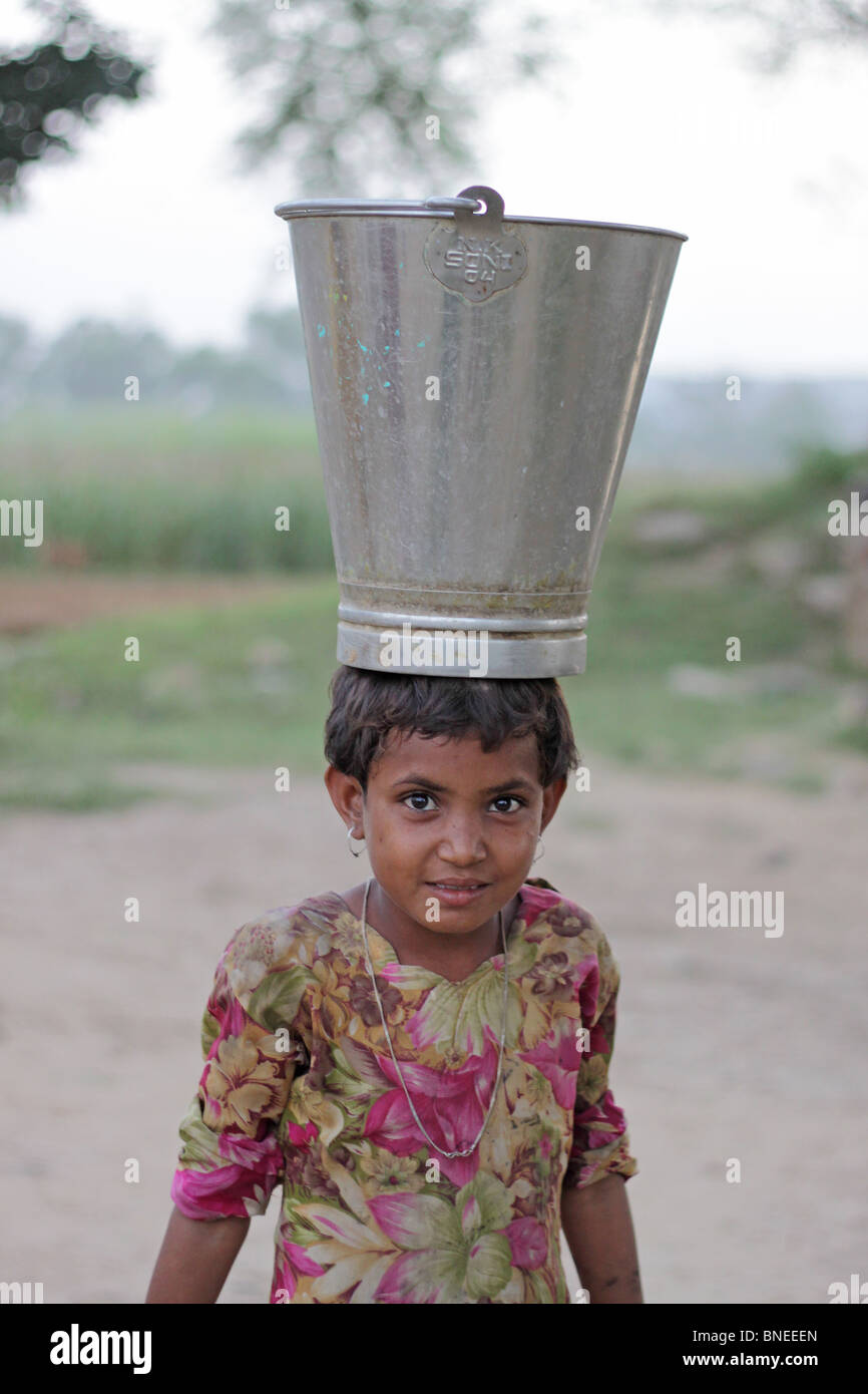 A young girl carrying a bucket on head in a remote village in Rajasthan ...