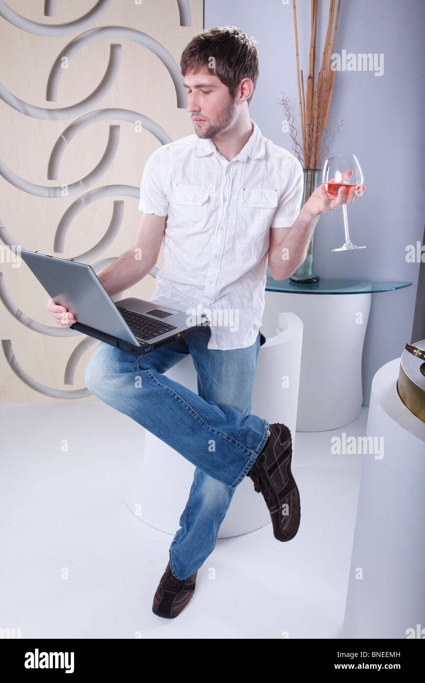 Young man sips while browsing Stock Photo - Alamy