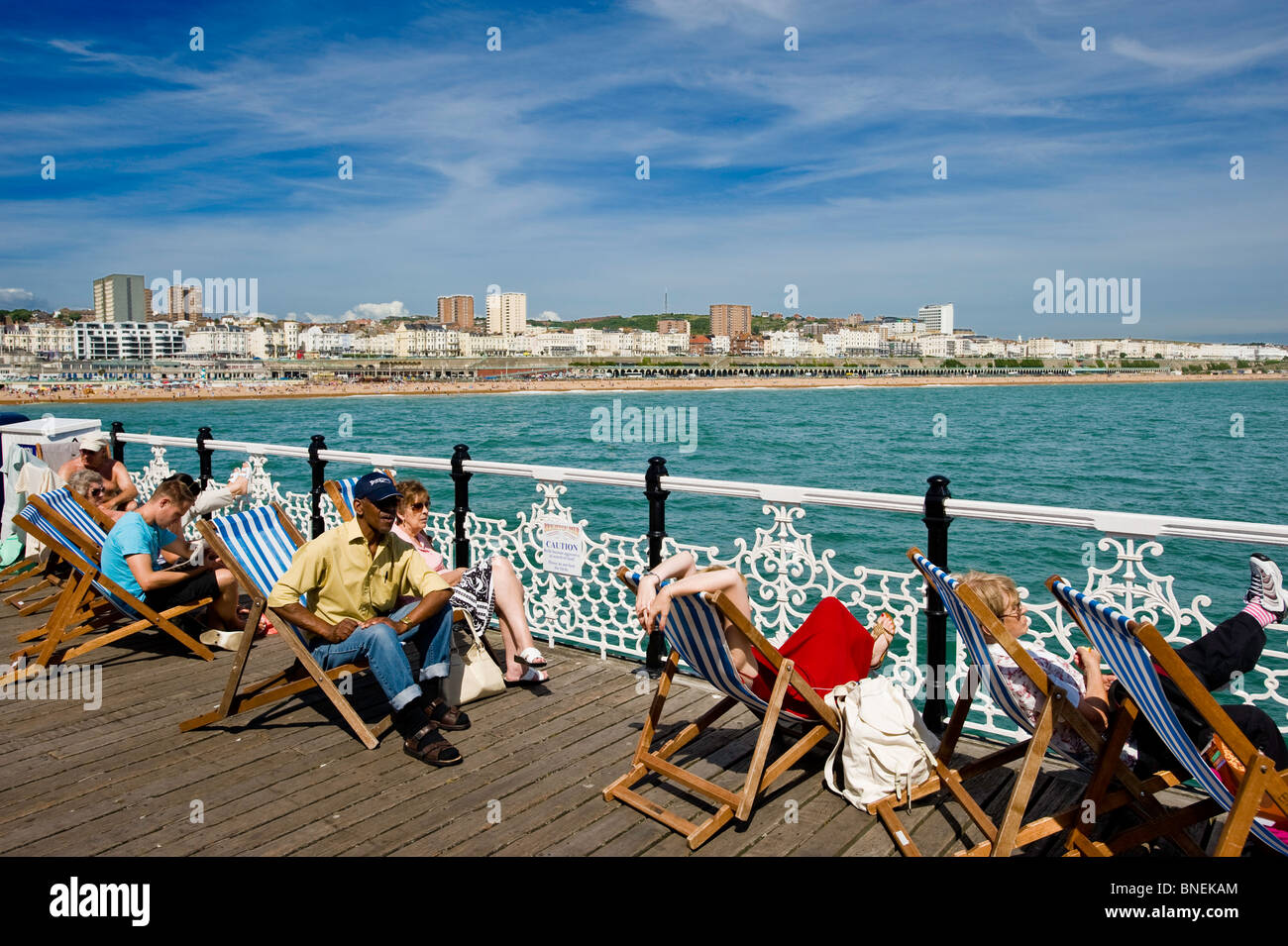 People relaxing in deck chairs on the pier, Brighton, East Sussex ...