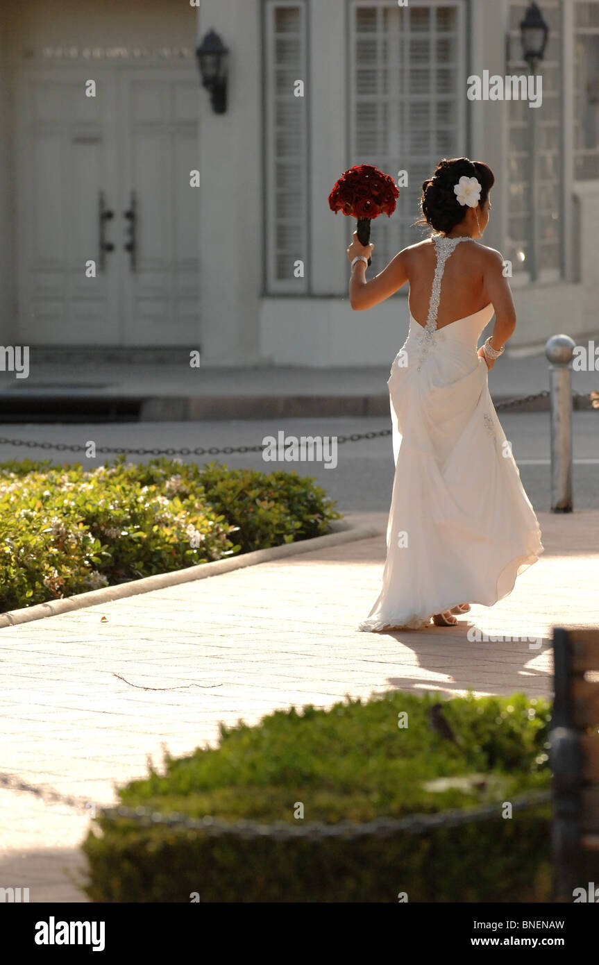Bride walking in her white dress and carrying her flowers Stock Photo ...