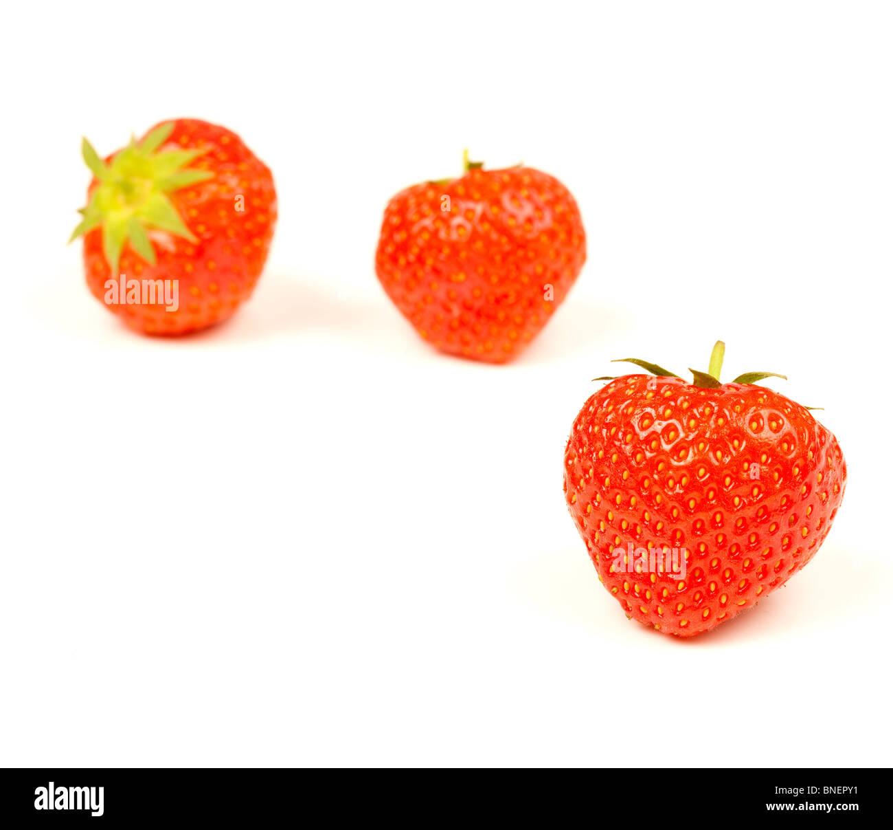 Three strawberries with only one in focus on white backround Stock ...