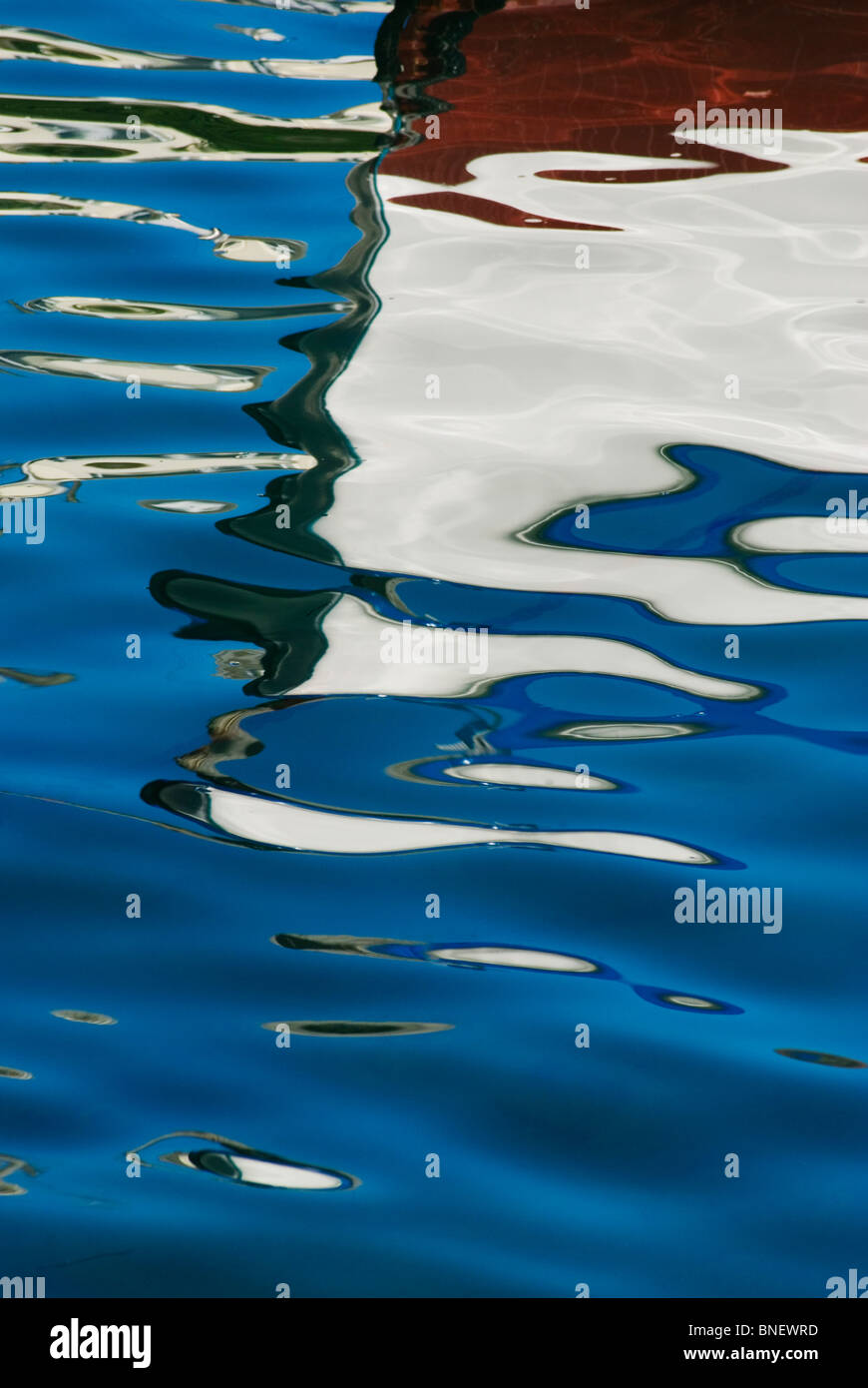 Ripples and reflections of a boat in the harbour at Coverack Cornwall ...