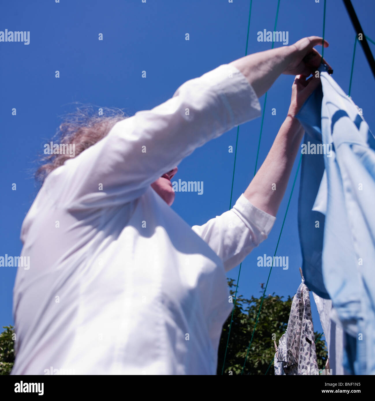 Woman hanging out washing on clothes drying line Stock Photo - Alamy