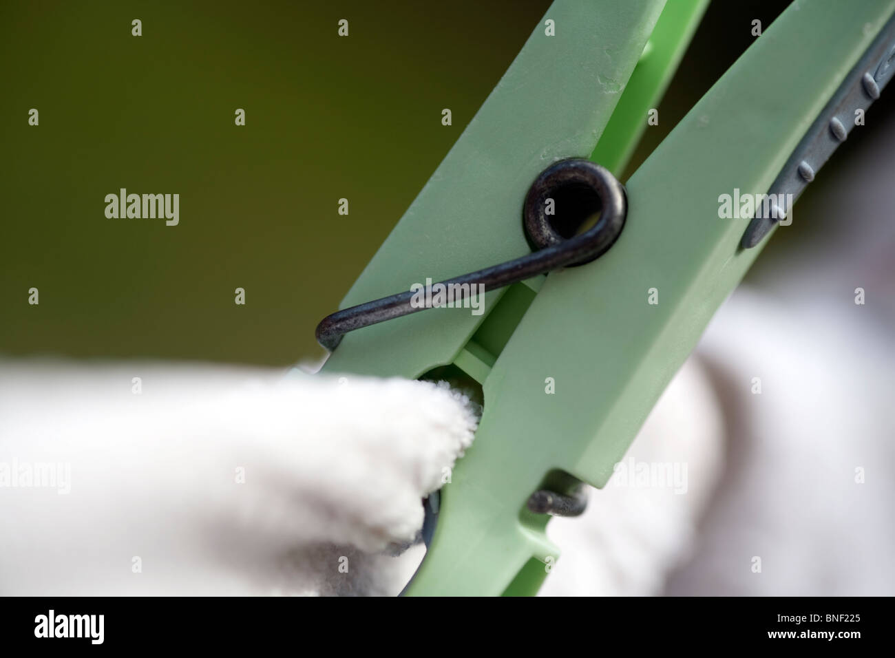 Close focus image of a green plastic clothes peg with white laundry on ...