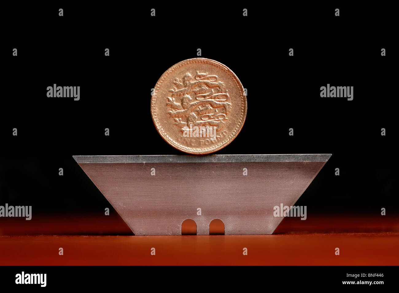 A one pound coin balancing on a razor blade Stock Photo - Alamy