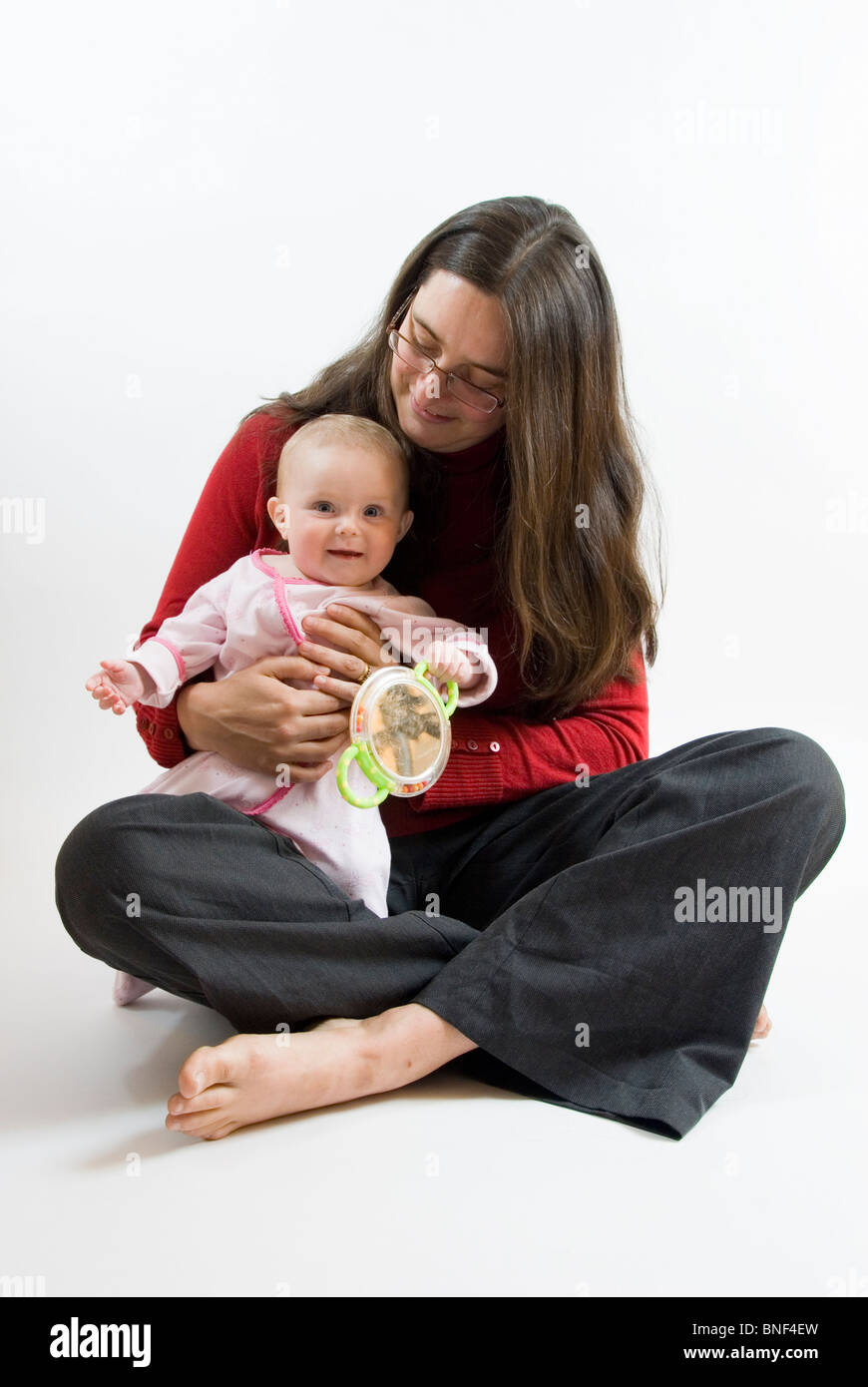 Portrait of Mother Sitting Cross Legged Holding Baby Girl, Isolated on ...