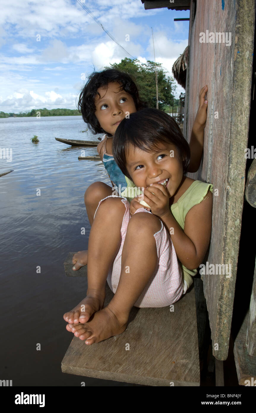 Two girls sitting on a plank, Peruvian Amazon, Tigre River, Loreto ...