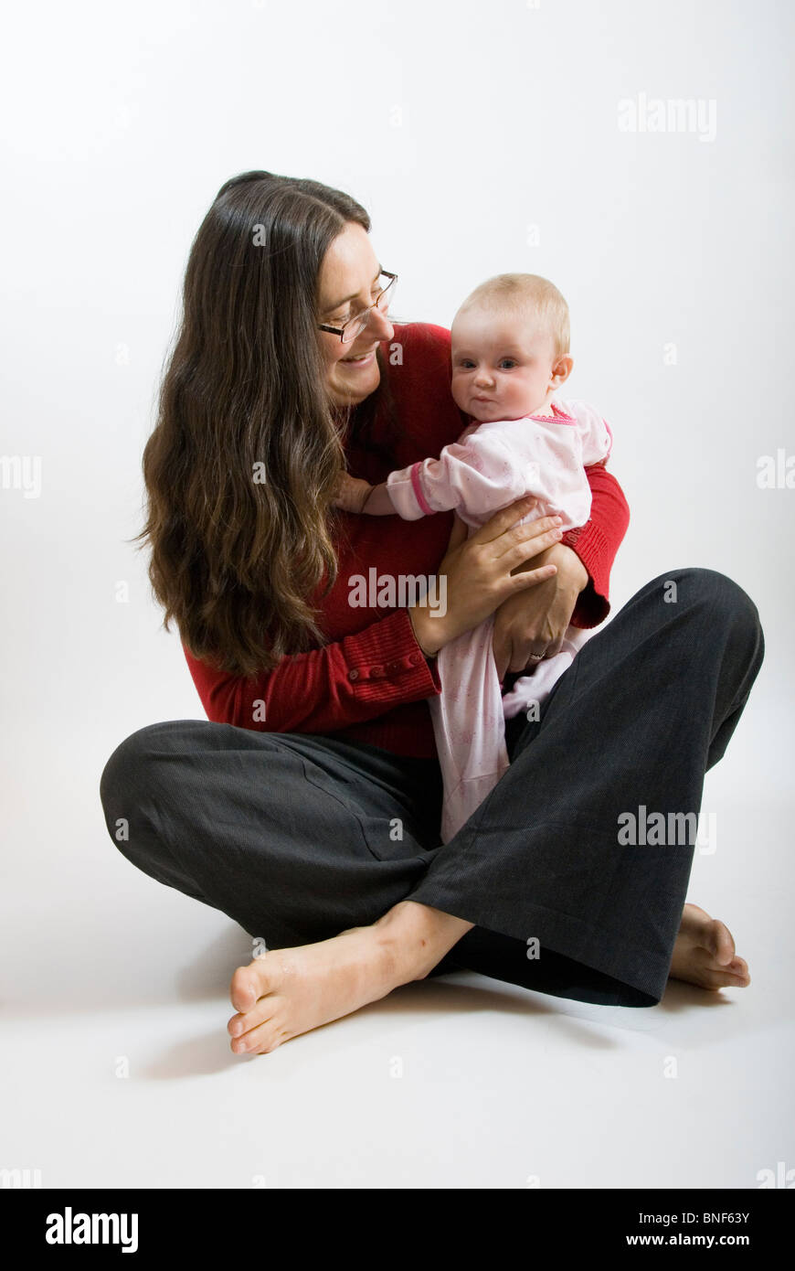 Portrait of Mother Sitting Cross Legged Holding Baby Girl, Isolated on ...