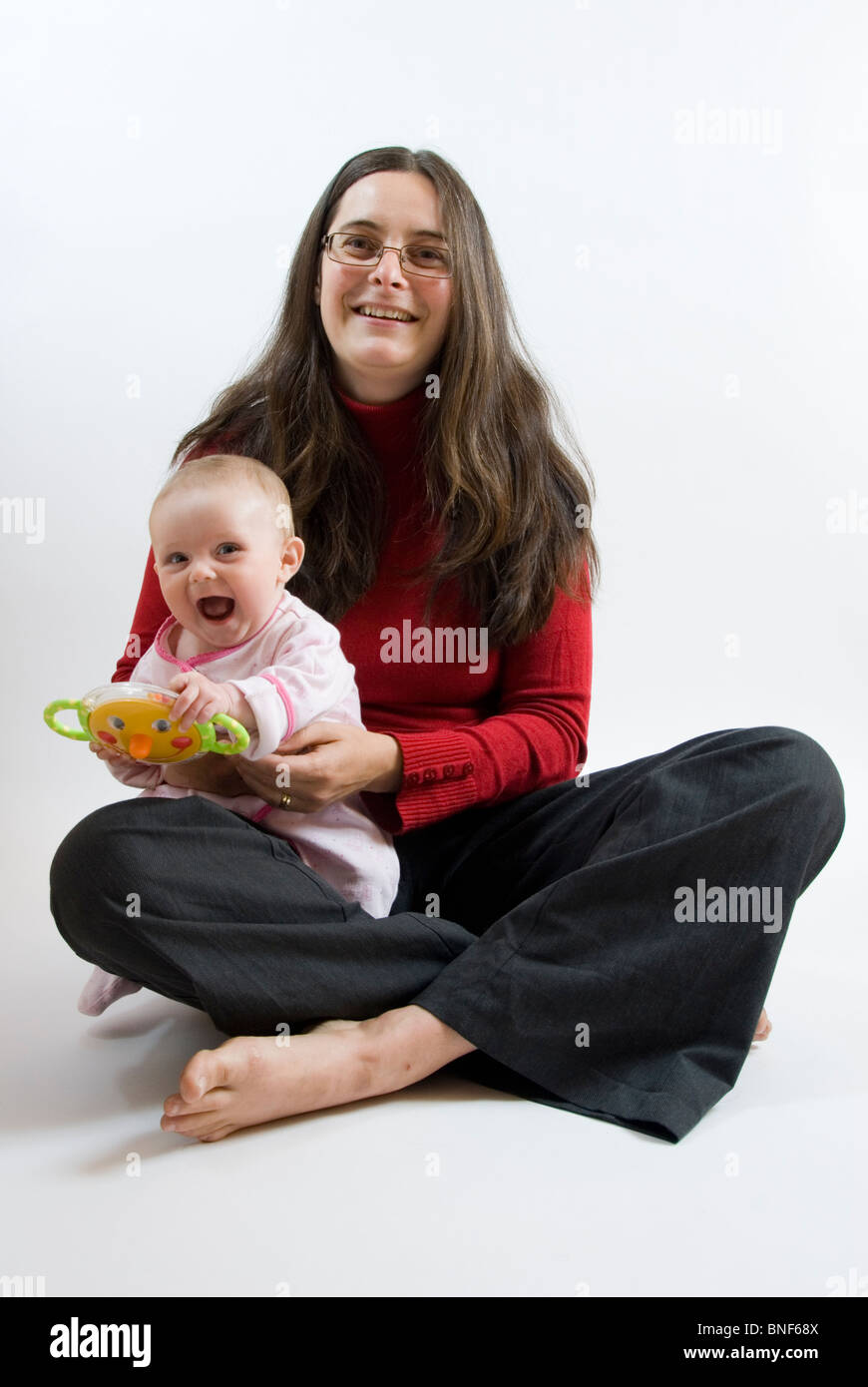 Portrait of Mother Sitting Cross Legged Holding Baby Girl, Isolated on ...