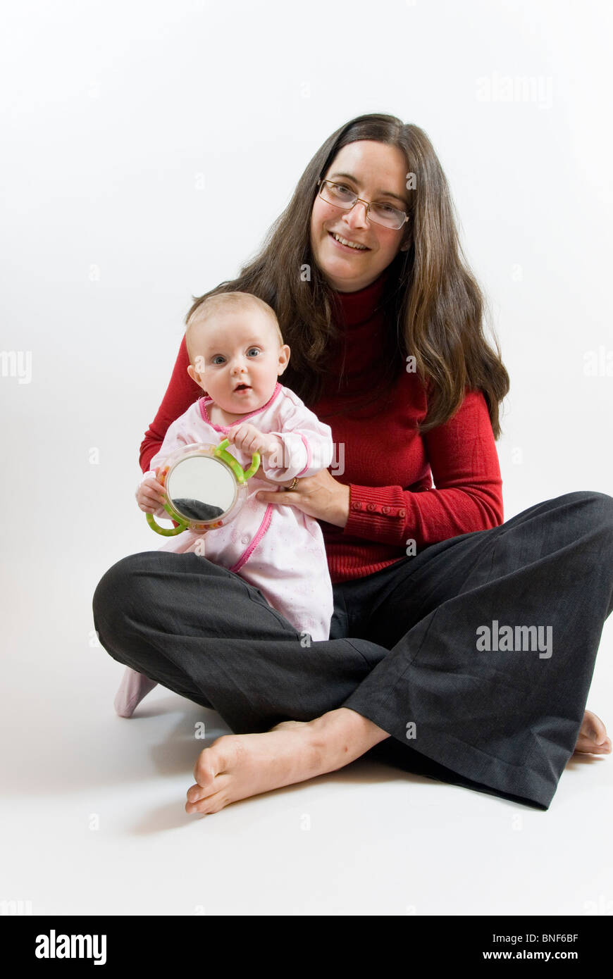 Portrait of Mother Sitting Cross Legged Holding Baby Girl, Isolated on ...