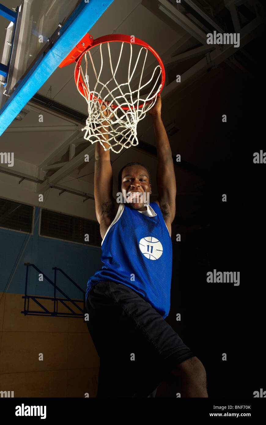 Basketball player swinging on goal hoop Stock Photo - Alamy