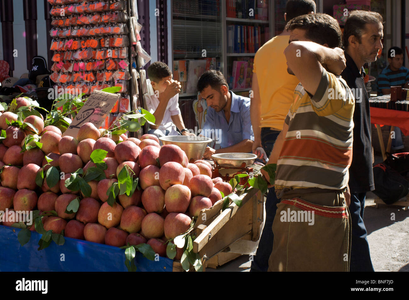 A street trader with his cart of red apples in the afternoon sun in ...