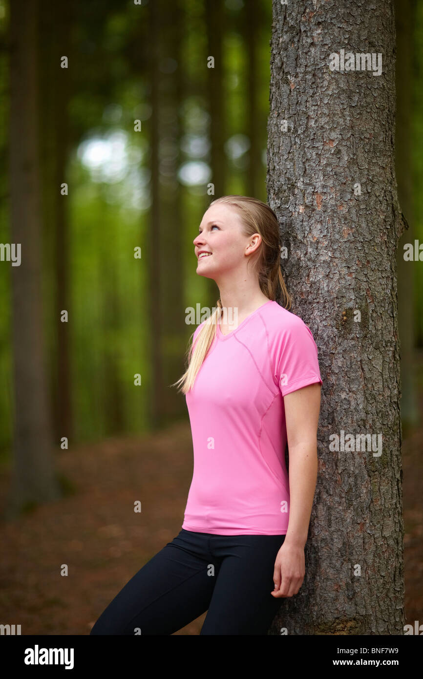 Woman running, leaning against tree Stock Photo - Alamy