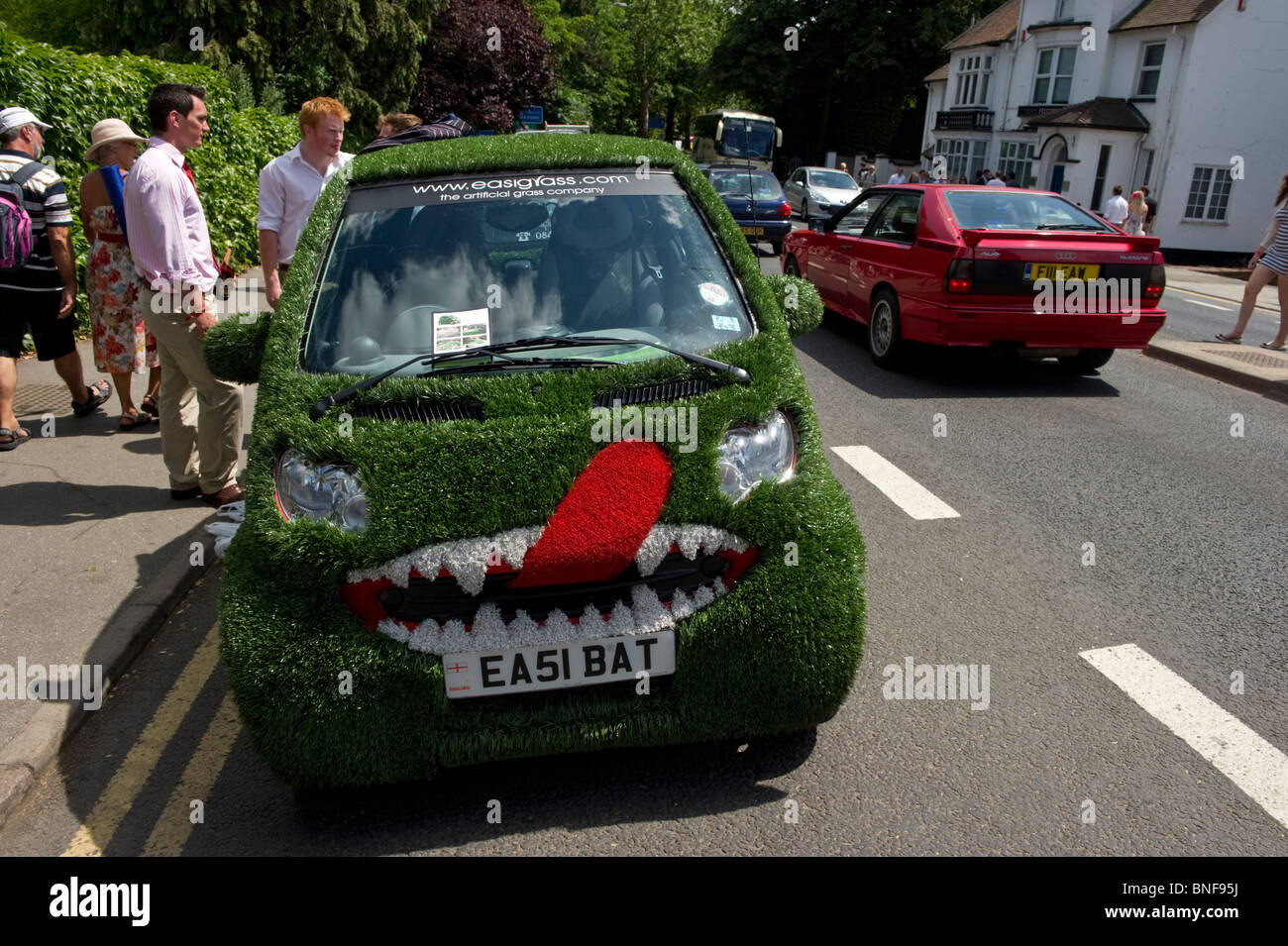Artificial green grass draped over a Smart car parked on a street in ...