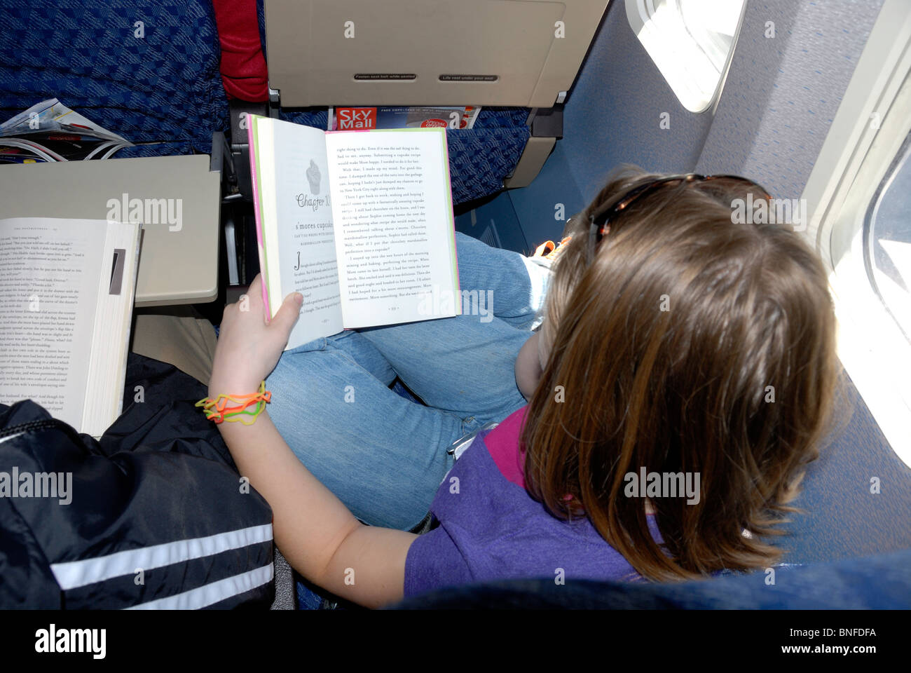 Young girl, age 10, reading a book while flying on an Airplane Stock ...
