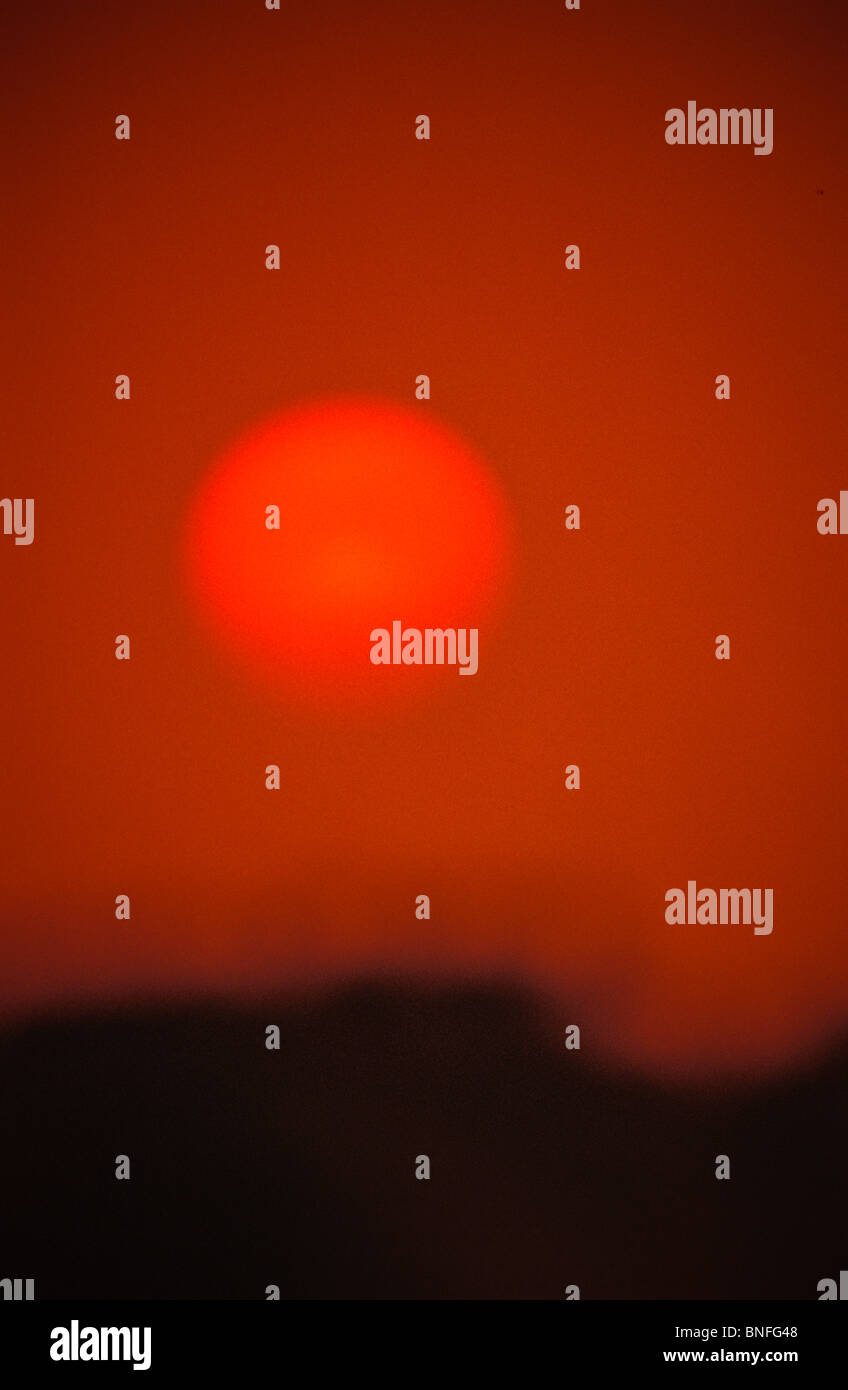 Bright red sun on horizon at sunset Stock Photo - Alamy
