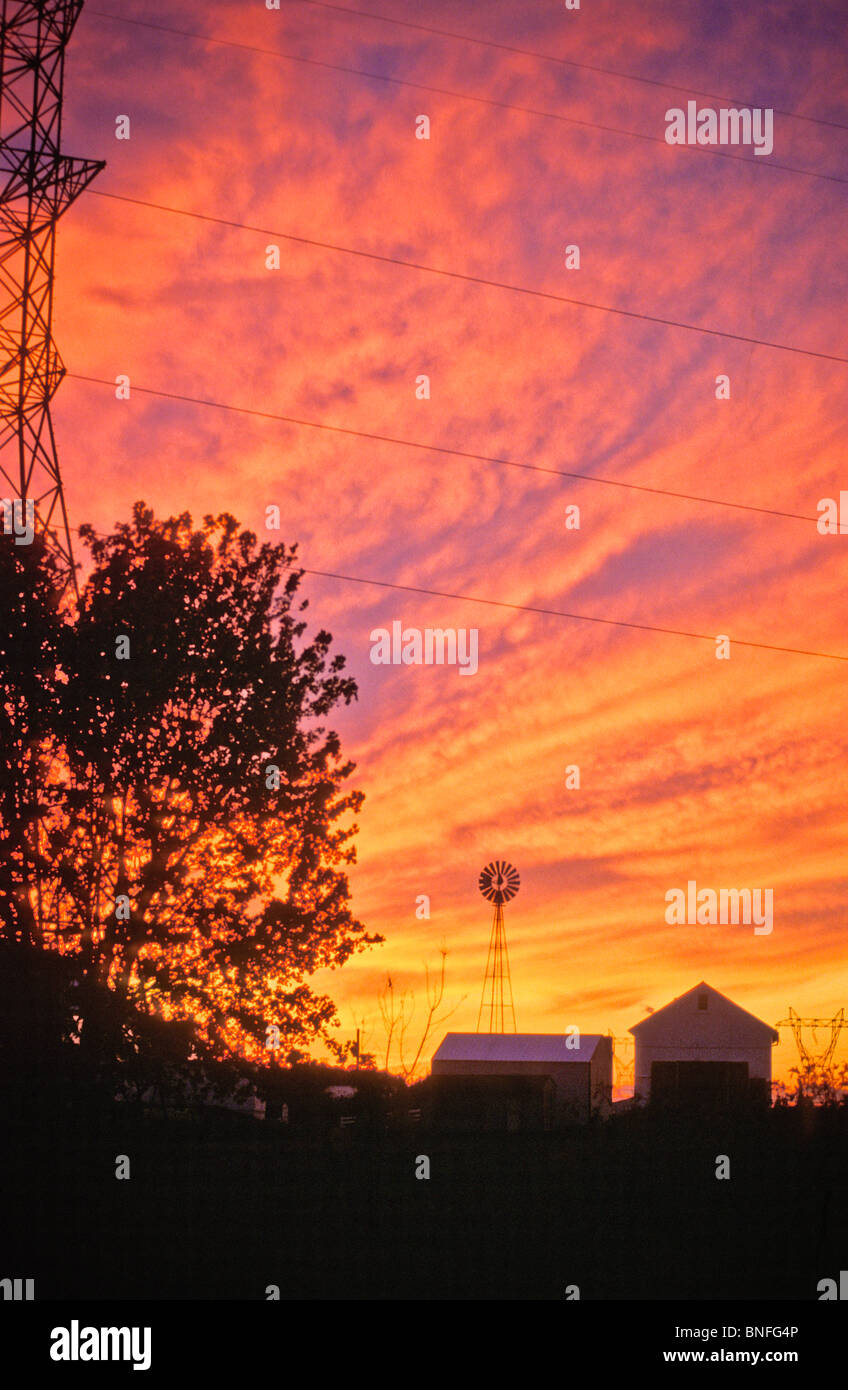 cloudy skies bright red sunset windmill farm buildings barns electric ...