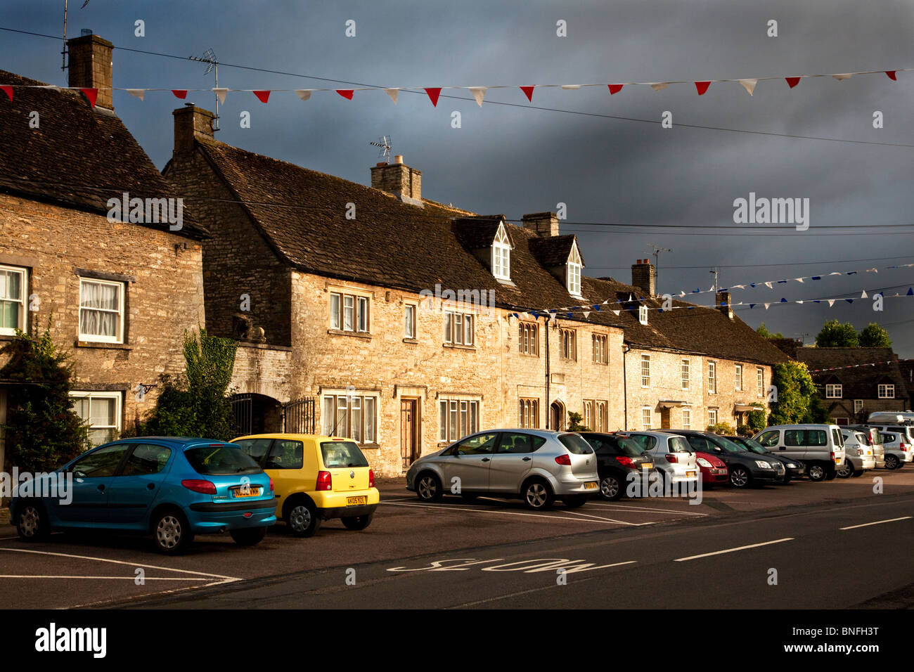 Dramatic stormy light falls on the mellow Cotswold stone houses along ...