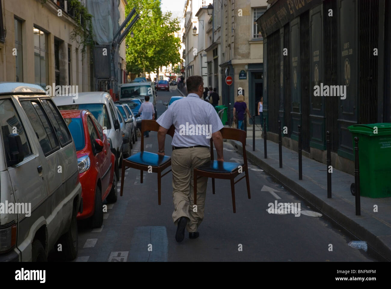 Man carrying chairs bought from Marais flea market Paris France Europe ...