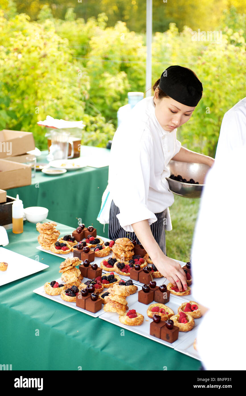 A chef plates baked desserts with cherries, raspberries, and ...