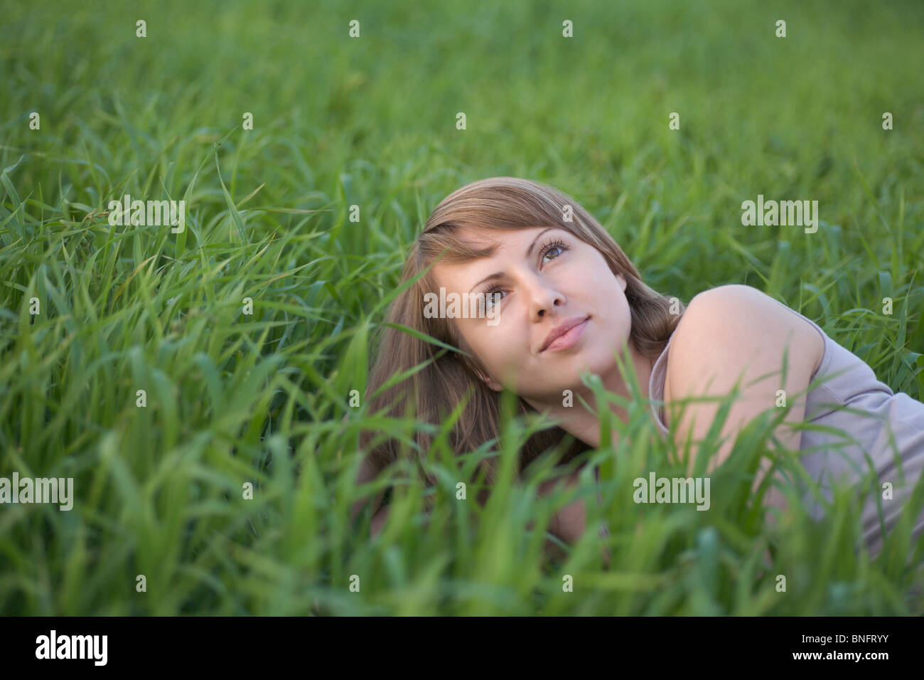 Young woman lies in a field of grass, looking up Stock Photo - Alamy