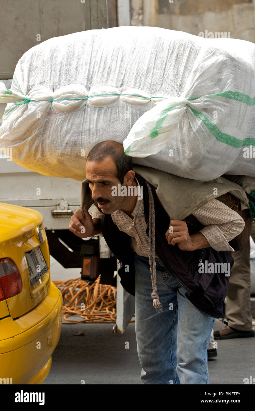 A 'hamal' (man who carries heavy loads) carries a heavy load of goods ...